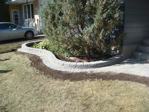 Roman Stack Stone retaining wall with paving stone border | The Lawn Salon